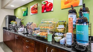 Buffet de café da manhã com diversos alimentos, um espaço para café e uma máquina de waffles.