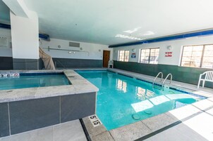 Piscina interna com água cristalina, prancha de mergulho e placa de proibição de mergulho.