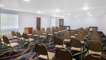Uma sala de conferência com fileiras de cadeiras, um pódio e uma tela de projetor.