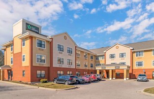 Um hotel com vários edifícios, um estacionamento cheio de carros e um céu limpo.