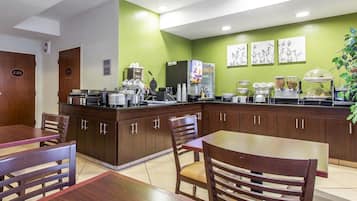 Cozinha moderna com armários de madeira, uma ilha central e um espaço de refeições com mesas e cadeiras.