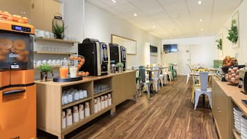 Um café moderno com piso de madeira, uma máquina de café e diversas opções de assentos, incluindo cadeiras e mesas.
