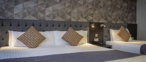 Quarto de hotel com parede estampada em padrão geométrico, cabeceira estofada e duas camas com almofadas combinando.