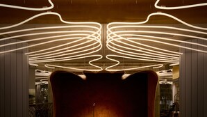 Decoração moderna com parede curva vermelha, área de estar e design de luminária no teto.