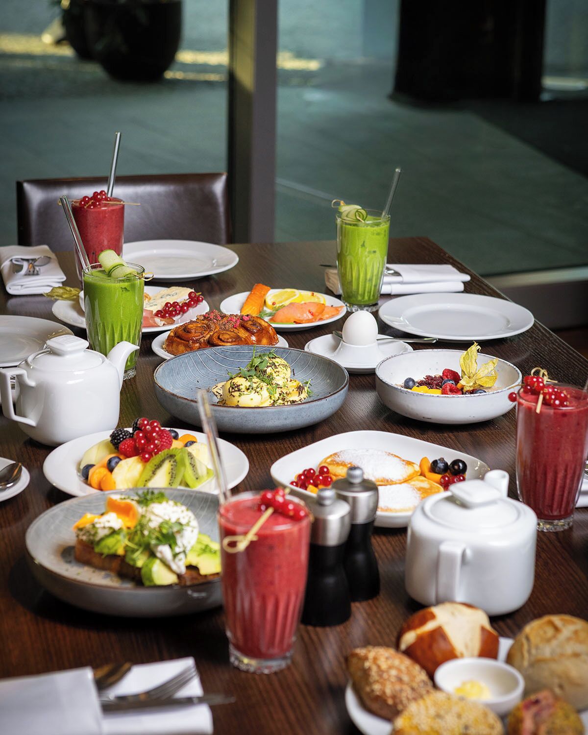 Um buffet de café da manhã com diversos pratos, bebidas e vista para o exterior.