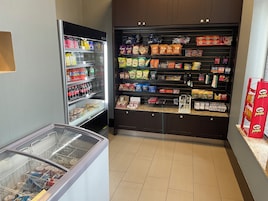 Área com lanches e bebidas, incluindo opções refrigeradas e diversos petiscos.