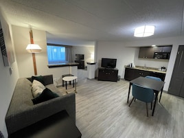 Uma sala de estar moderna com um sofá, uma mesa de jantar e uma televisão.