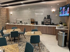 Um balcão de café da manhã moderno com assentos e uma TV exibindo notícias.