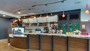 Uma área de bar moderna com balcão de madeira, luminárias pendentes e um quadro de menu, além de um aquário.