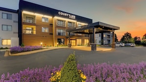 Um hotel Courtyard by Marriott com design moderno, várias varandas e entrada coberta.