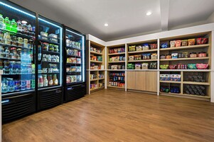 Uma área bem organizada para lanches e bebidas, com geladeiras e prateleiras repletas de diversos produtos.