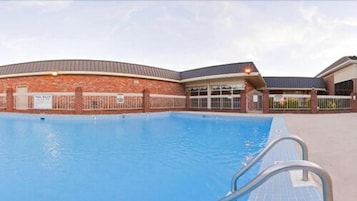 Piscina com muro de tijolos e área coberta.