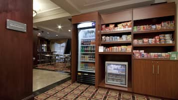 Um mercado de hotel com balcões refrigerados e prateleiras cheias de lanches e bebidas.