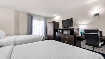 Quarto de hotel com duas camas, televisão de tela plana, micro-ondas, escrivaninha com luminária e minibar.