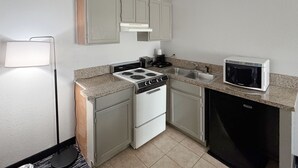 Uma cozinha compacta com fogão, micro-ondas, pia e armários.