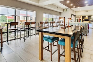 Uma área de jantar moderna com uma mesa comunitária grande, banquetas de bar e vista para o exterior.