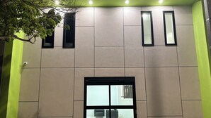 Entrada de um edifício com porta de vidro, câmera de segurança e uma pequena janela acima da porta.