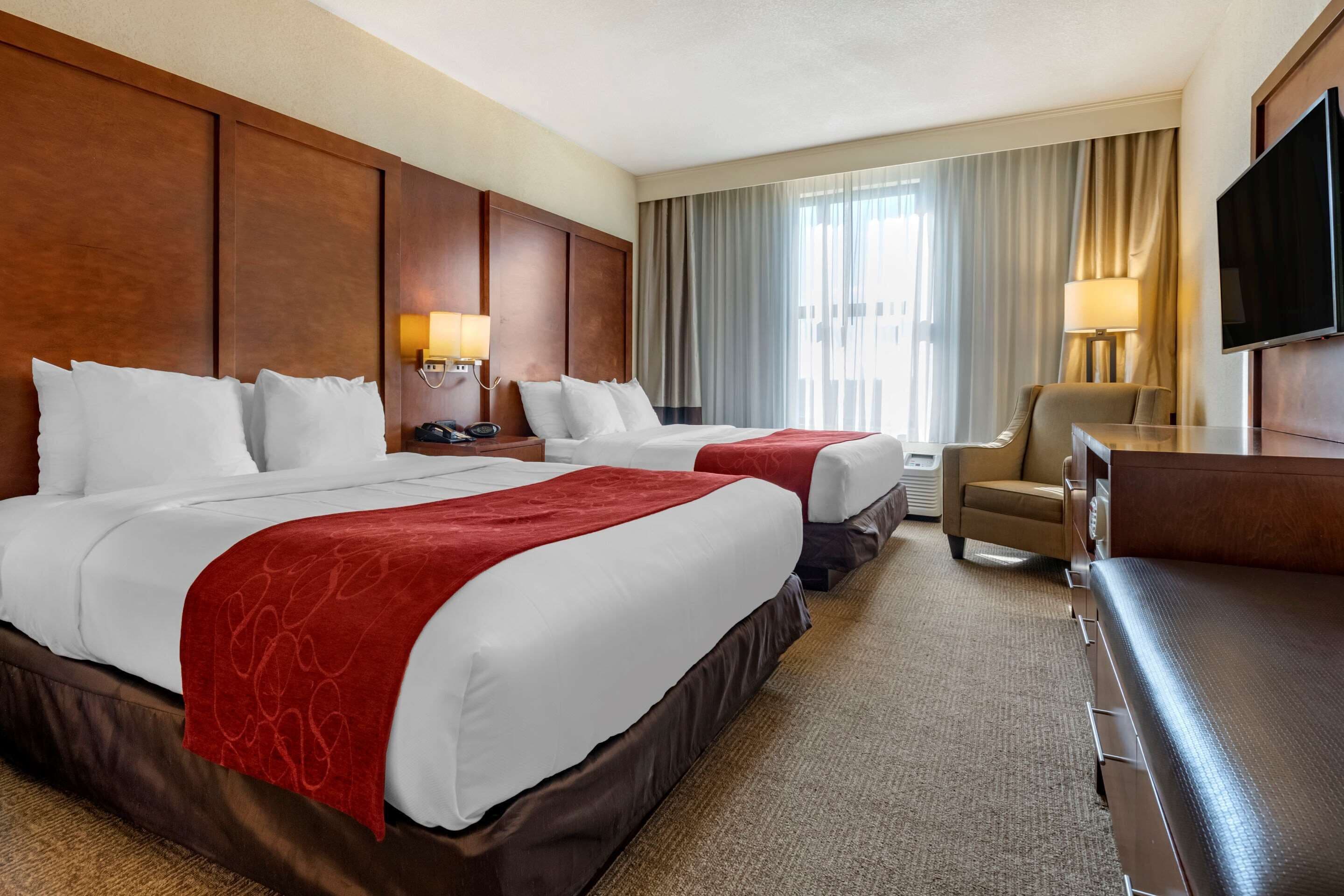 Quarto de hotel com duas camas, televisão, escrivaninha e uma cadeira.