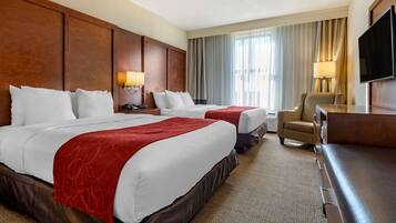 Quarto de hotel com duas camas, televisão, escrivaninha e uma cadeira.