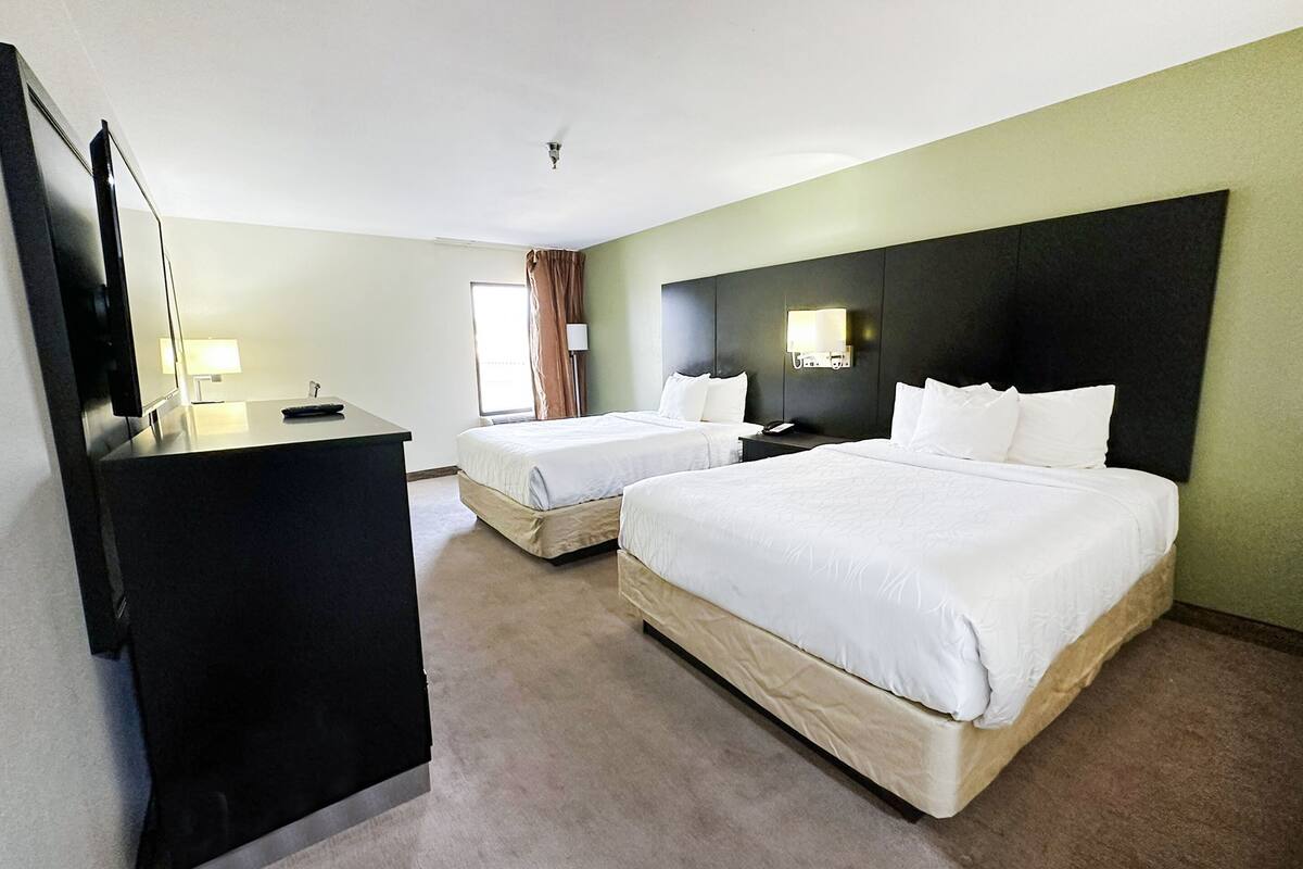 Quarto de hotel com duas camas, uma escrivaninha e uma televisão.