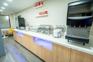 Uma mesa de pequeno-almoço com torradeira, máquina de café e dispensador de água.
