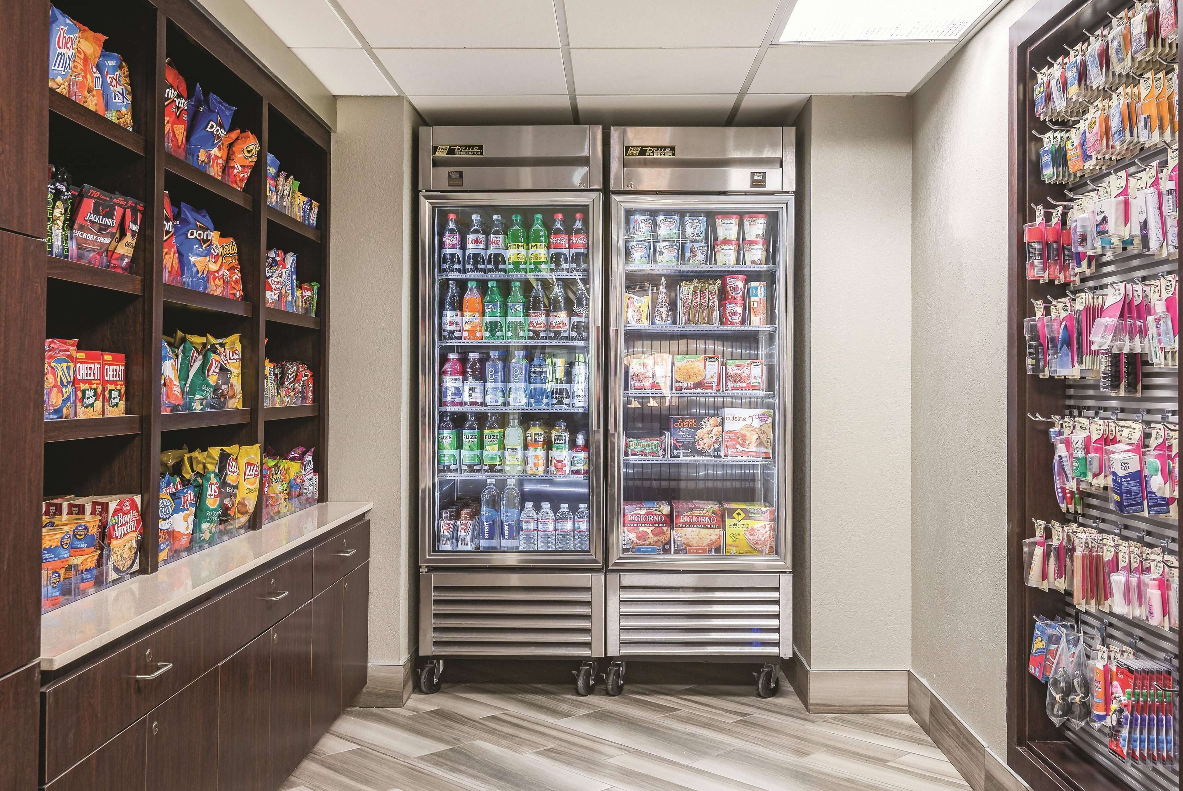 Uma estação de lanches e bebidas com máquinas de refrigerantes e prateleiras repletas de petiscos e produtos embalados.
