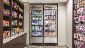 Uma estação de lanches e bebidas com máquinas de refrigerantes e prateleiras repletas de petiscos e produtos embalados.