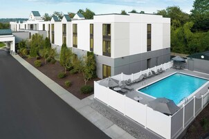 Um hotel moderno com piscina, área de estar ao ar livre e um jardim bem cuidado.