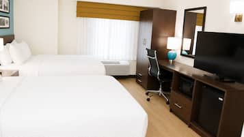 Quarto de hotel com duas camas, uma escrivaninha com cadeira, televisão e minibar.