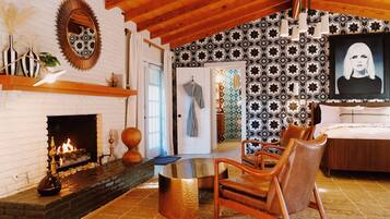 Uma sala de estar acolhedora com lareira, uma área de refeições e um quarto com televisão.