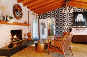 Uma sala de estar acolhedora com lareira, uma área de refeições e um quarto com televisão.