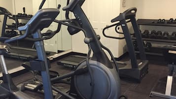 Uma academia com várias esteiras, um suporte de halteres e um aparelho Vision Fitness.