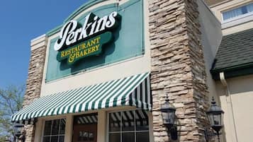 Um restaurante e padaria Perkins com fachada de pedra e toldo verde.