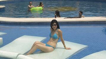 Piscina com bordas revestidas e uma pessoa sentada na borda.