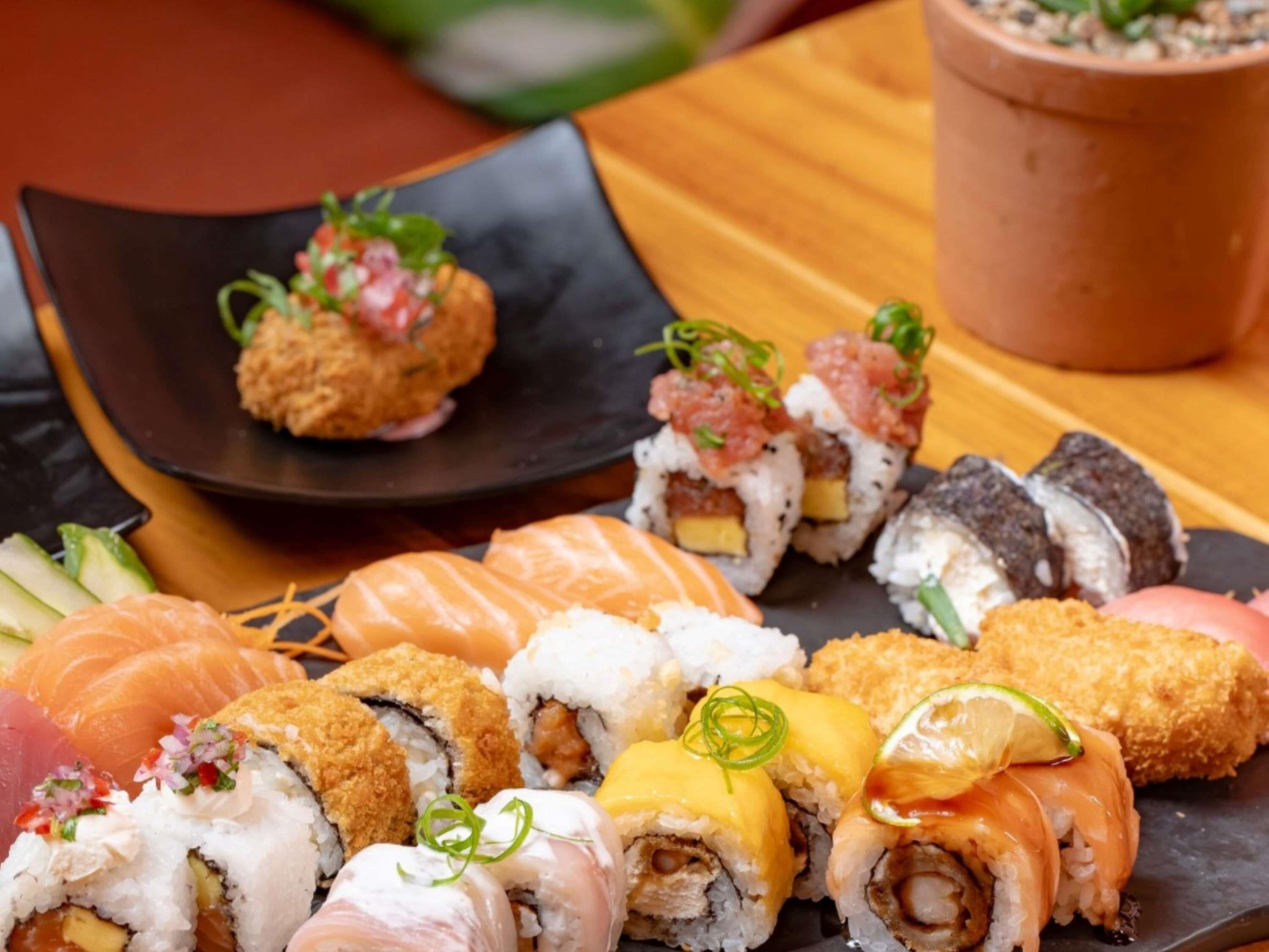 Diversos tipos de sushi em um prato de ardósia preta.