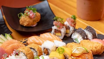 Diversos tipos de sushi em um prato de ardósia preta.