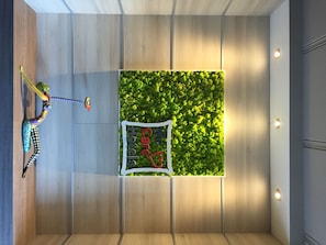 Interior de hotel com piso de madeira, parede verde com sinal indicando "We Care Hotels" e uma escultura colorida.