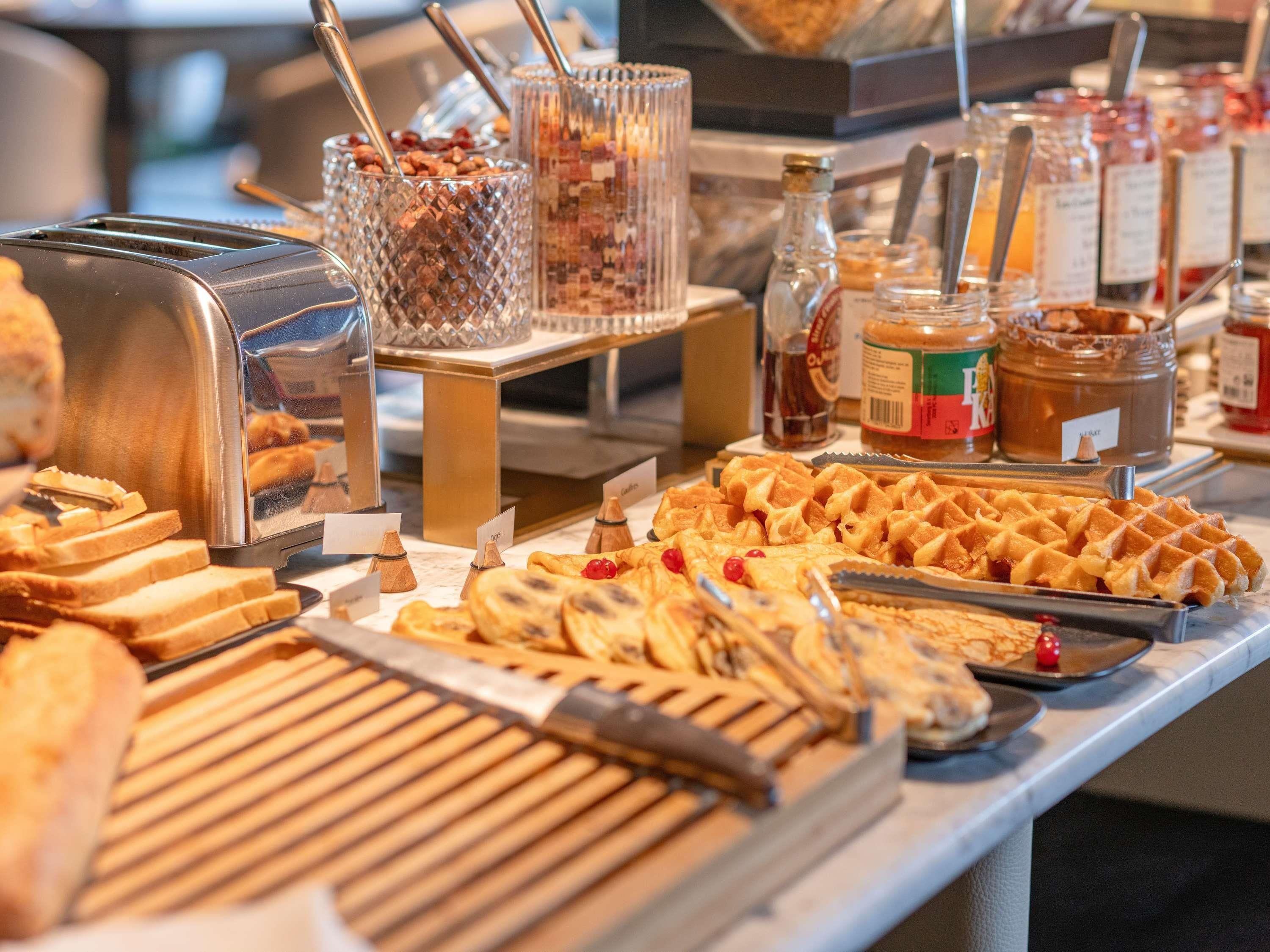 Um buffet com diversos alimentos, incluindo waffles, sanduíches e uma variedade de acompanhamentos.