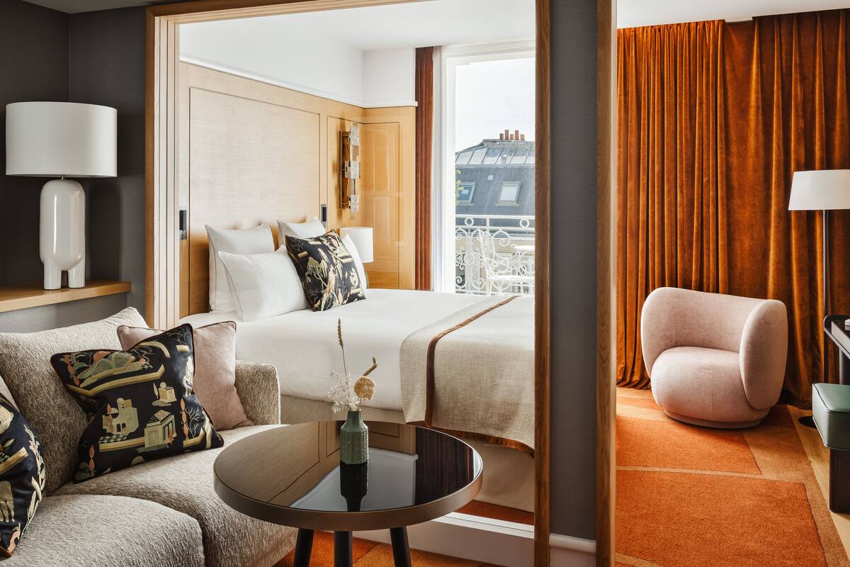 Quarto de hotel com cama, sofá, mesa pequena e uma cadeira.