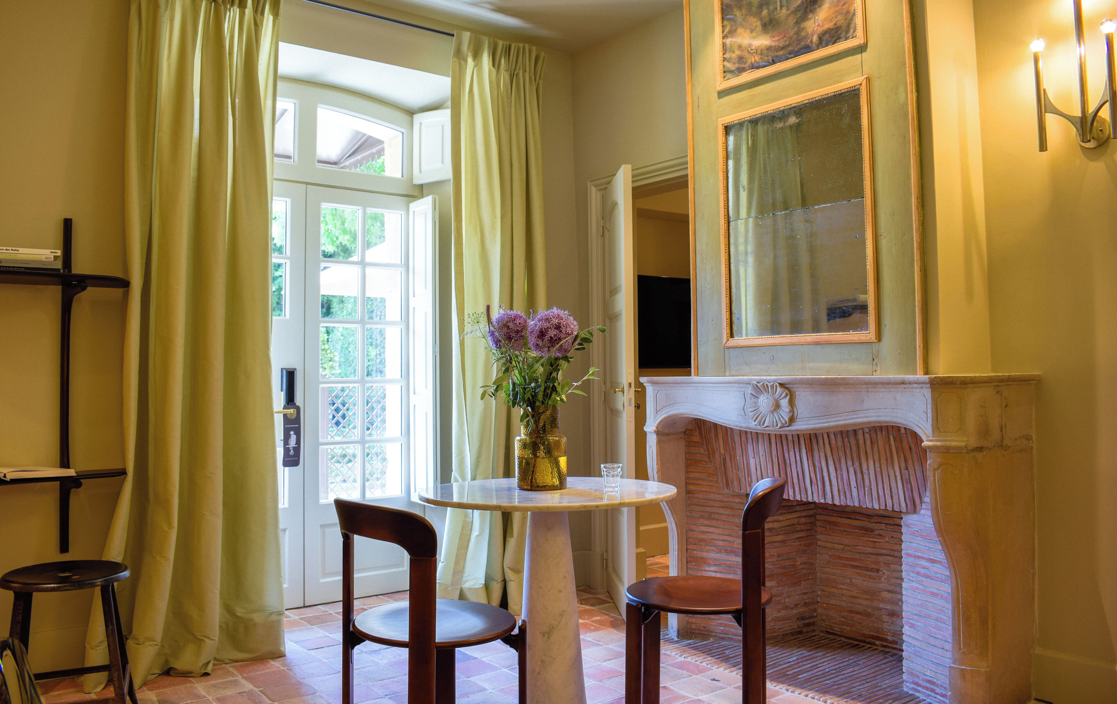 Um quarto com lareira, uma mesa com cadeiras e uma porta que dá para o exterior.