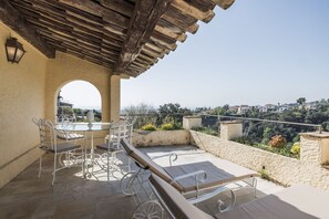 Um terraço com mesa e cadeiras, uma pérgula e vista para a cidade.