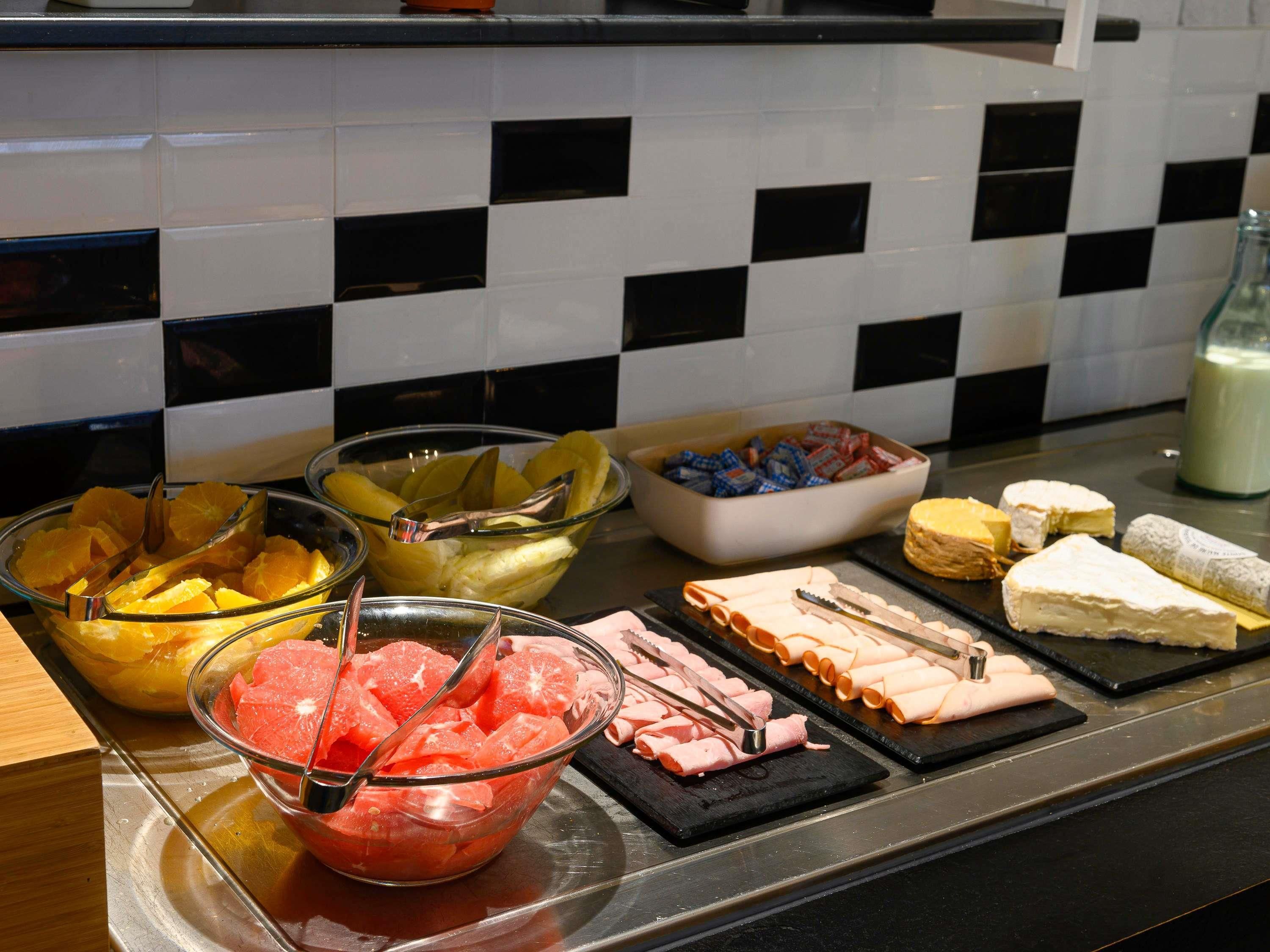 Buffet com diversos alimentos, incluindo frutas, queijos e carnes.