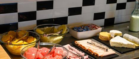 Buffet com diversos alimentos, incluindo frutas, queijos e carnes.