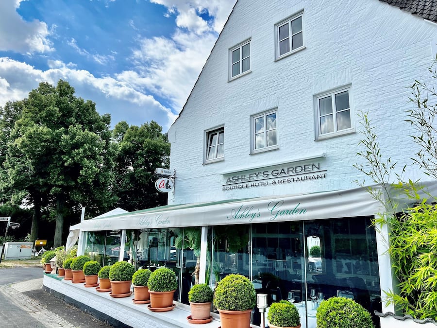 Um edifício branco com uma placa que diz "Ashley's Garden Boutique Hotel & Restaurant".