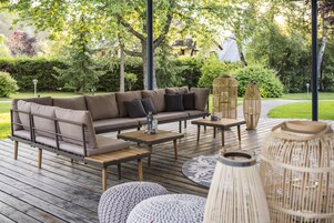 Um deck externo com um sofá, duas mesas e lanternas decorativas.