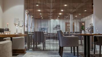 Uma sala de jantar moderna com teto alto, divisórias de vidro e móveis contemporâneos.