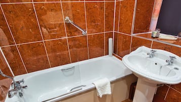 Uma casa de banho com banheira, lavatório e espelho.