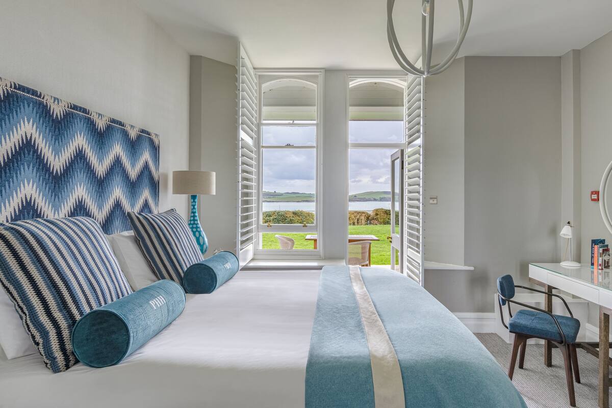 Quarto com cama, escrivaninha e vista para o exterior.