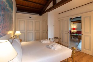Quarto com uma cama grande, duas mesas de cabeceira com abajures e teto de madeira.