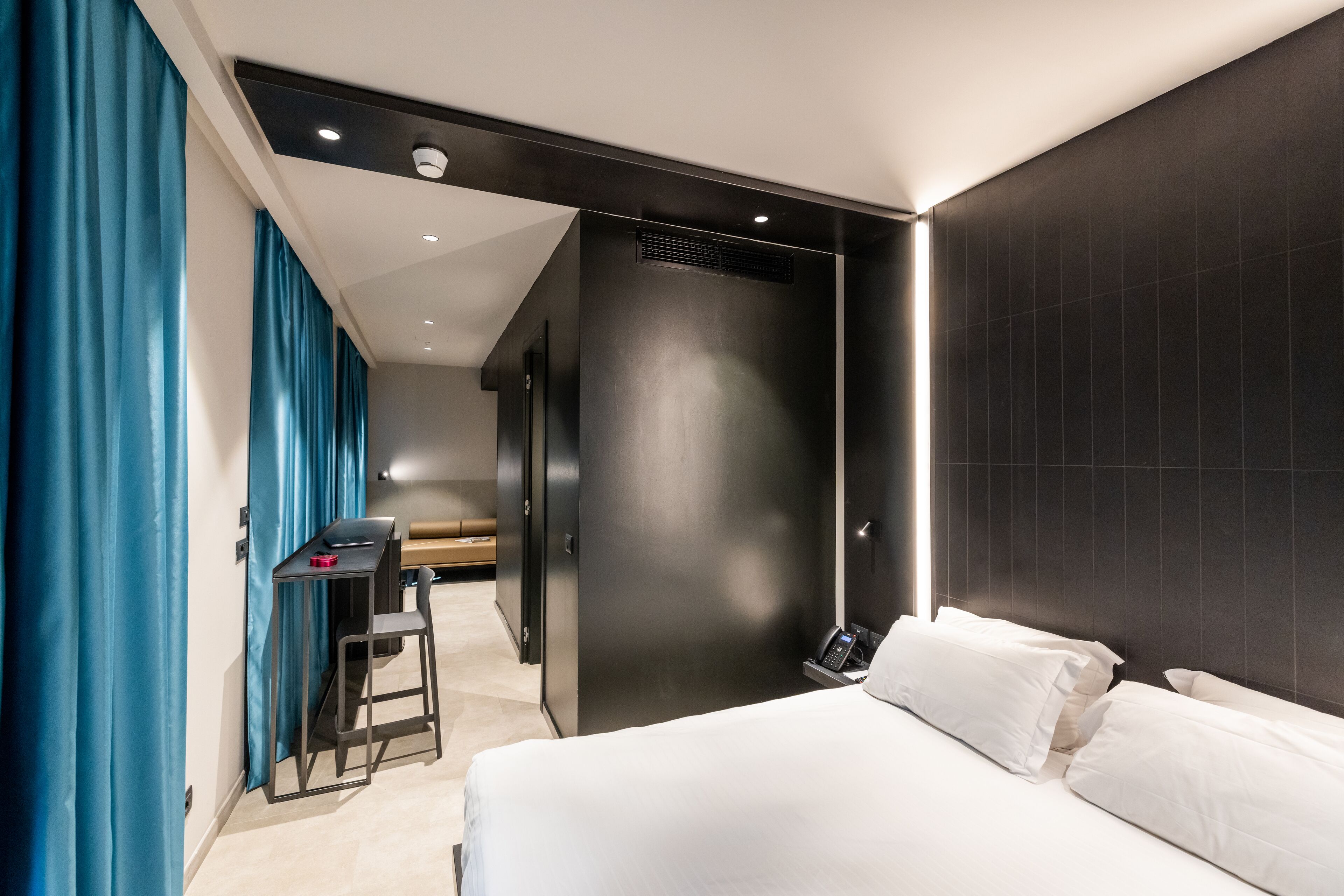 Quarto de hotel moderno com uma cama grande, uma mesa e uma cadeira.